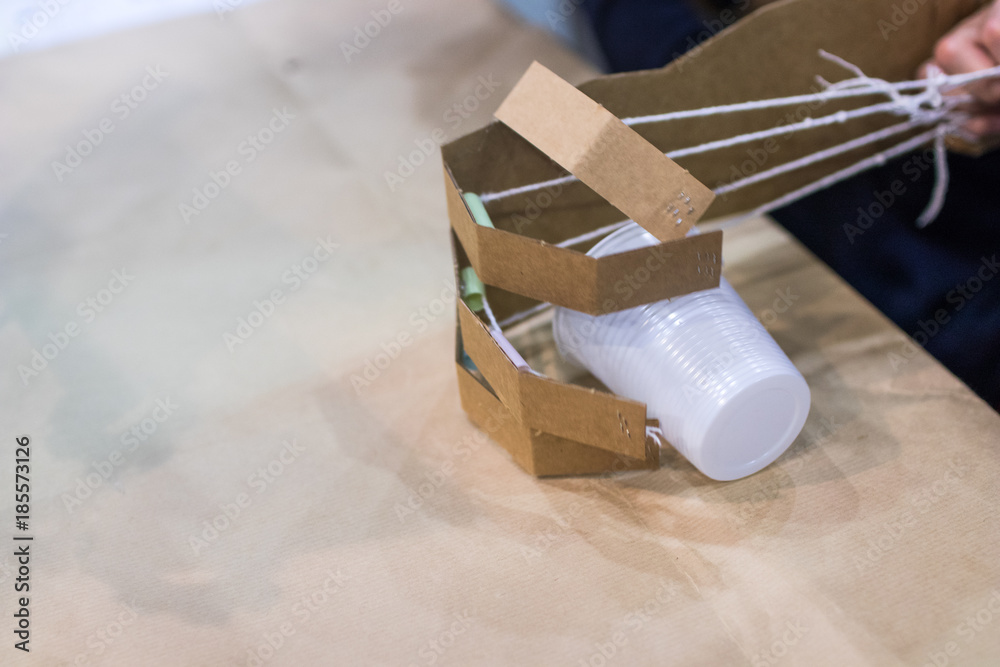 Child takes a plastic cup with a cardboard mechanical arm. STEM ...