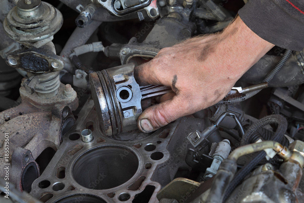 Car mechanic holding old piston at engine after disassembly, part ...