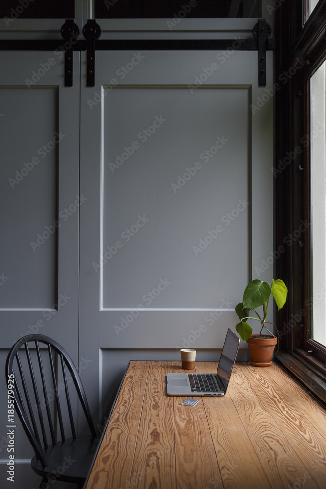 Wooden desk with laptop, plant and cup in the clean interior of a ...