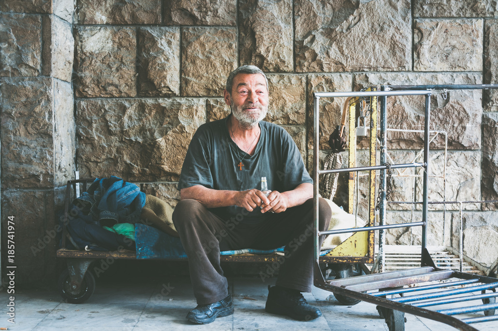 Homeless man. Happy and smiling homeless man sitting in the shadow of ...