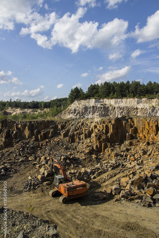 Excavator and basalt columns rocks. Heavy industry. Stone excavation ...