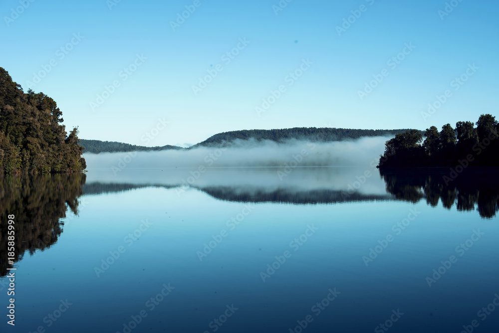 Lago en calma con reflejo de niebla y árboles. Stock Photo | Adobe Stock