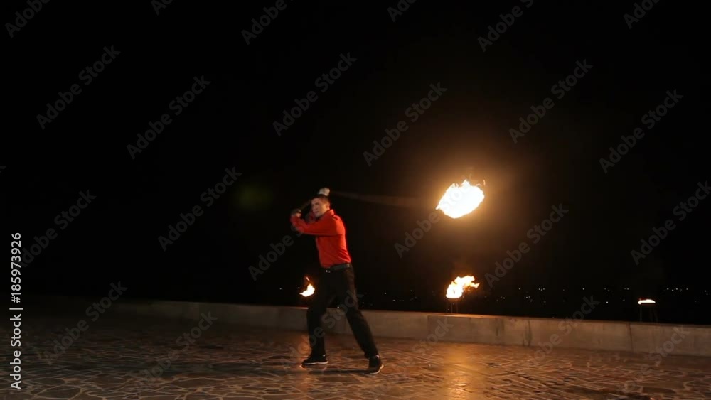 Artist man rotates the fireball.Man twist fiery circles on a fire show ...