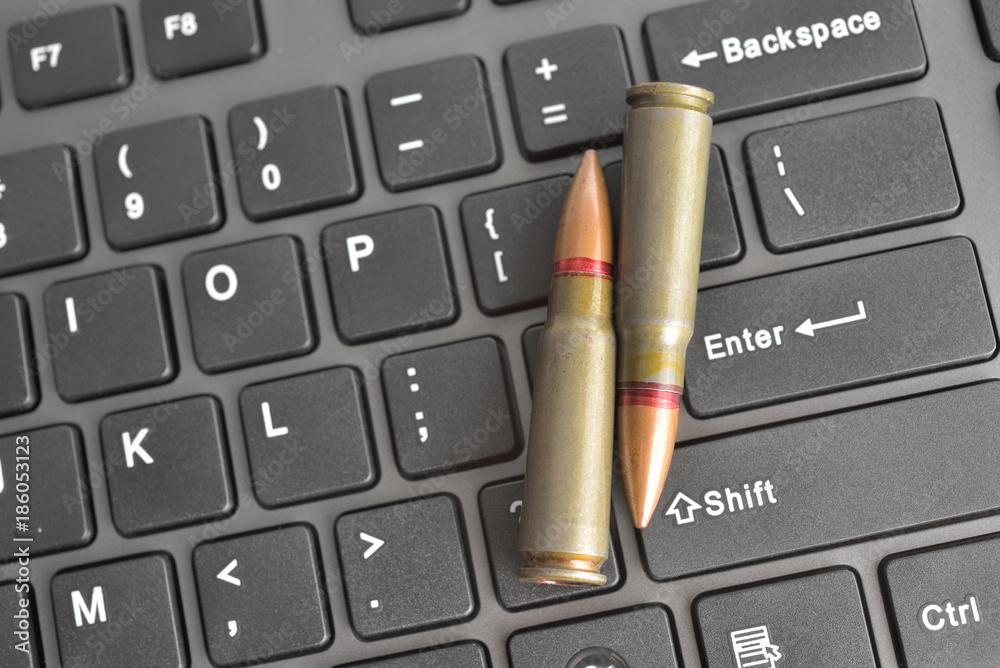 Internet dangers concept. Close up of bullets on computer keyboard ...