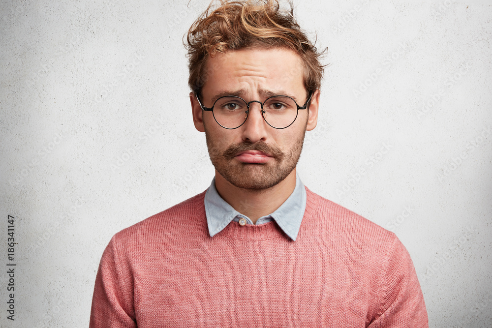 Foto Stock Stressed sorrorful bearded man curves lower lip as sustains ...
