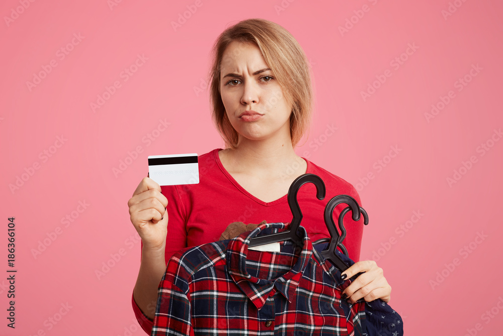 Foto de Displeased female shopaholic takes variety of clothes on ...