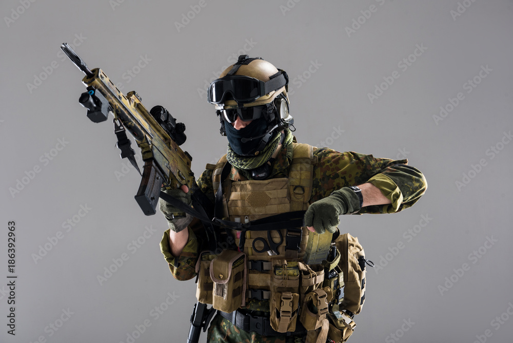 Portrait of severe soldier wearing uniform while keeping assault rifle ...