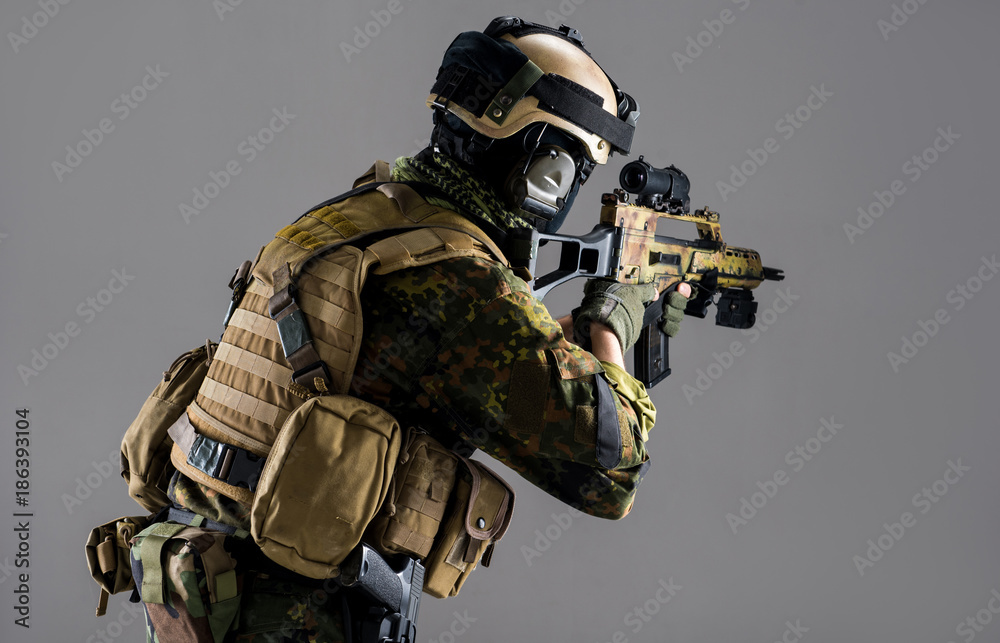 Side view serious male pointing assault carbine while wearing ...