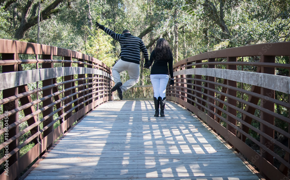 Foto de Man jumping for joy kicking heels together walking on bridge ...