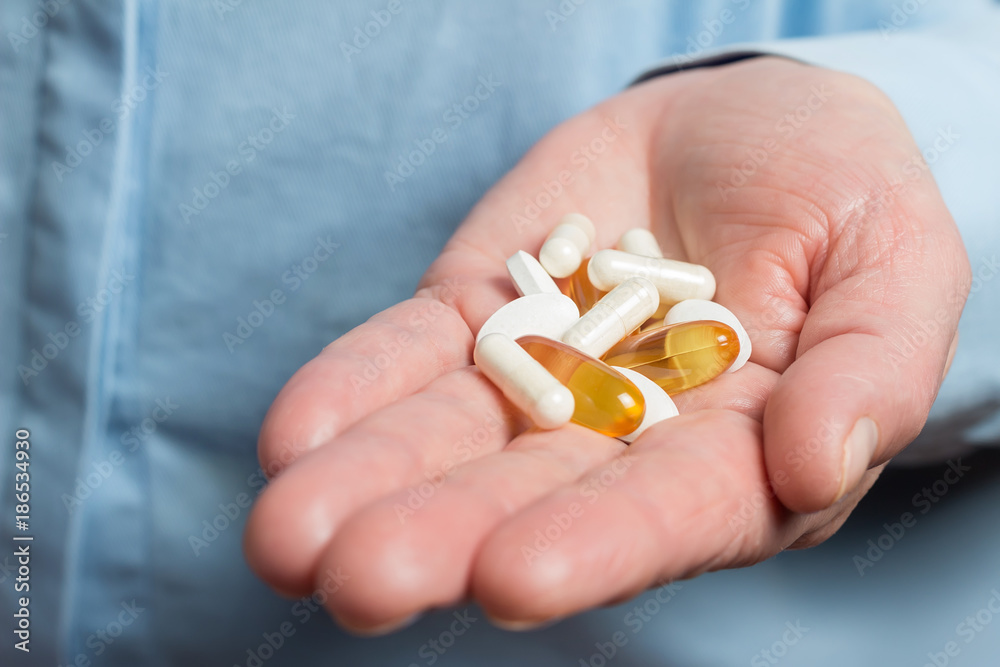 Woman take in the hand variety medication pills, yellow capsules of ...