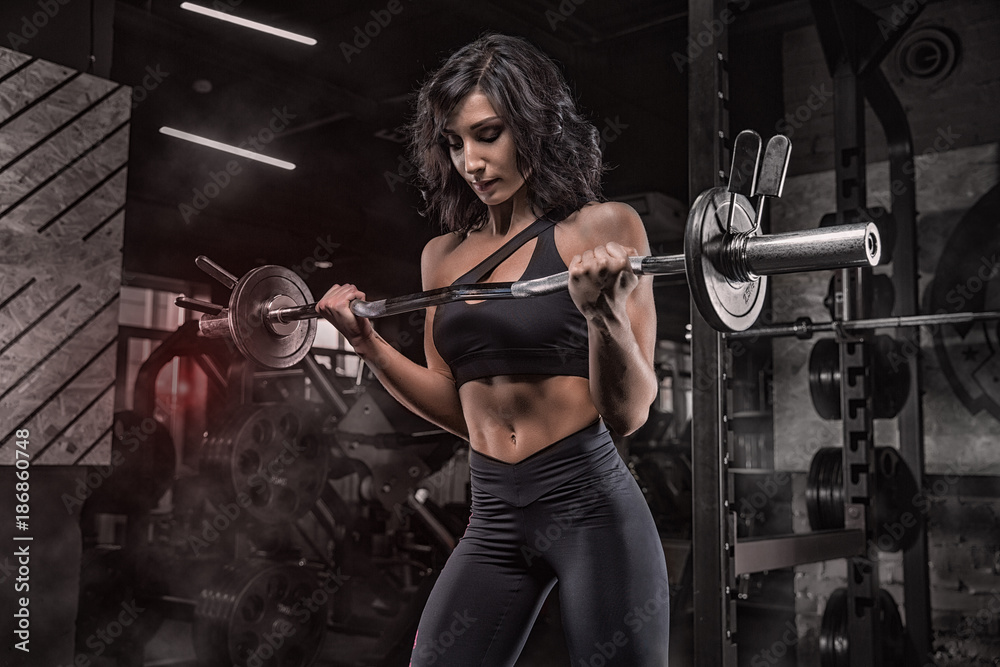 Young beautiful girl bodybuilder doing exercises in the gym using a ...