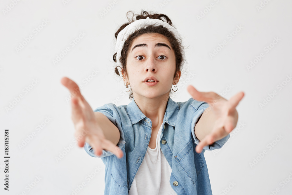 Young female dressed in denim shirt with dark and wavy hair in bun ...