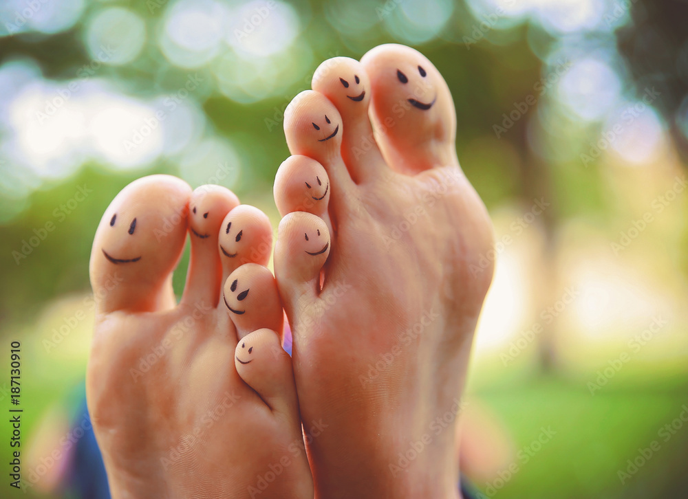 smiley faces on a pair of feet on all ten toes in a park on a hot ...