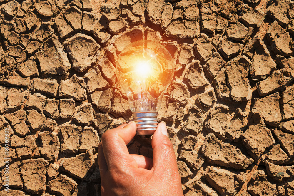 hand holding light bulb on soil arid. concept power solar energy in ...