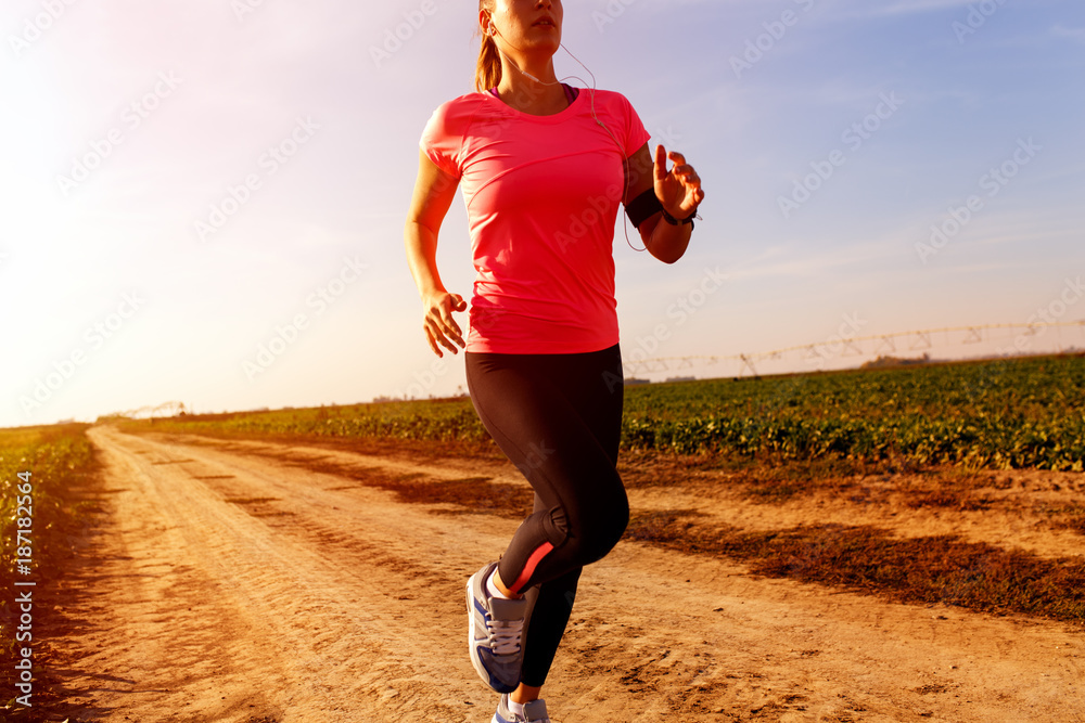 Athletic woman running on rural road. Stock Photo | Adobe Stock