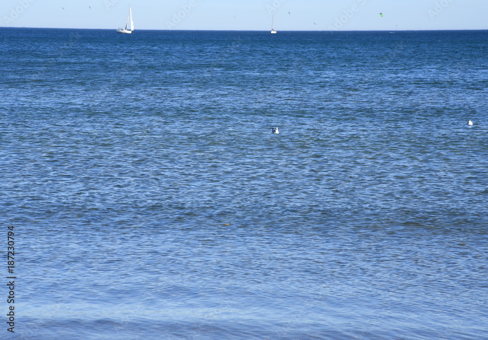 Blick auf das weite, blaue Meer mit zwei winzigen weißen Booten am ...