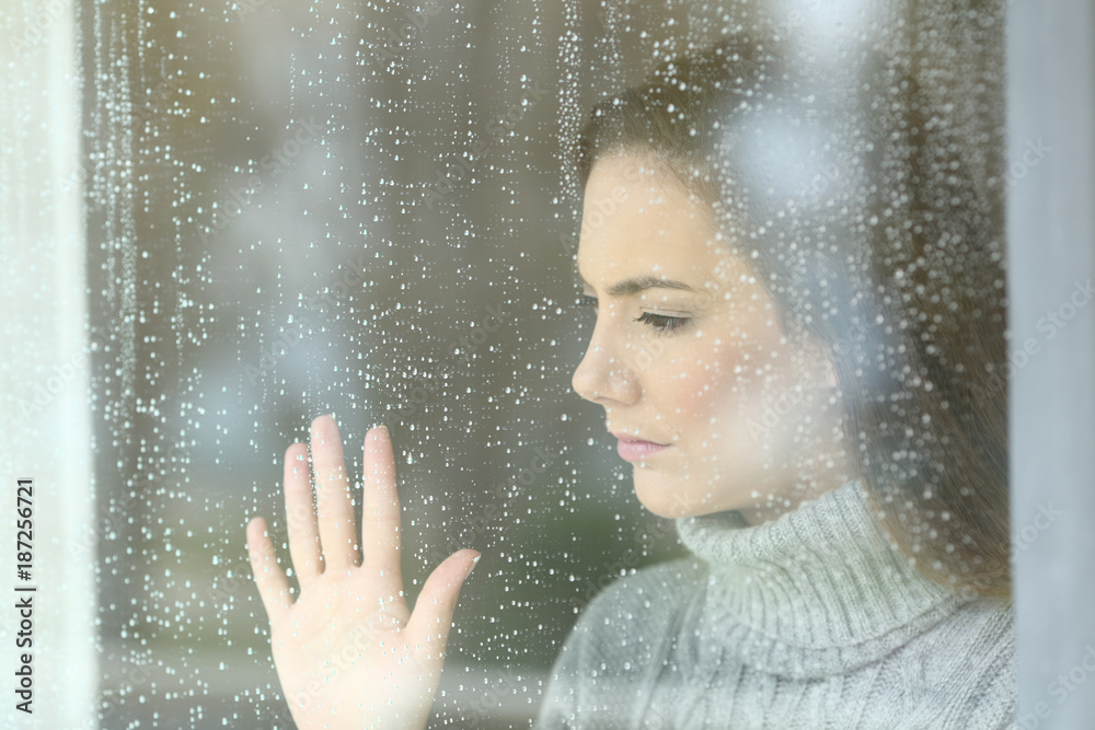Sad girl looking through a window in a rainy day Stock-Foto | Adobe Stock