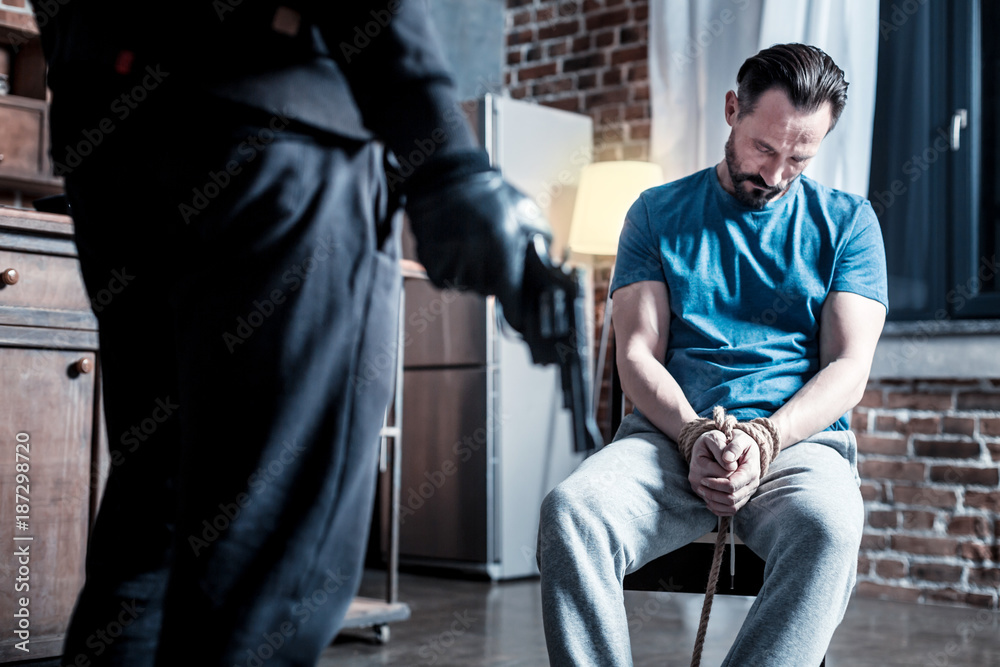 Terrified. Scared unconscious bearded man sitting with his hands tied ...