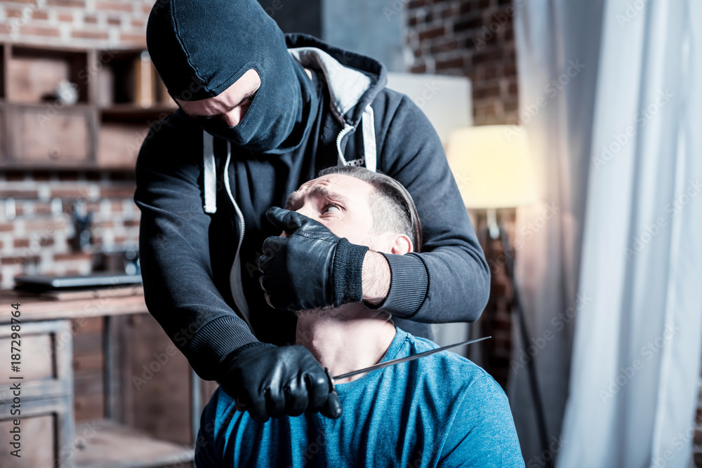 Killer. Terrible ferocious masked criminal closing mans mouth with his ...