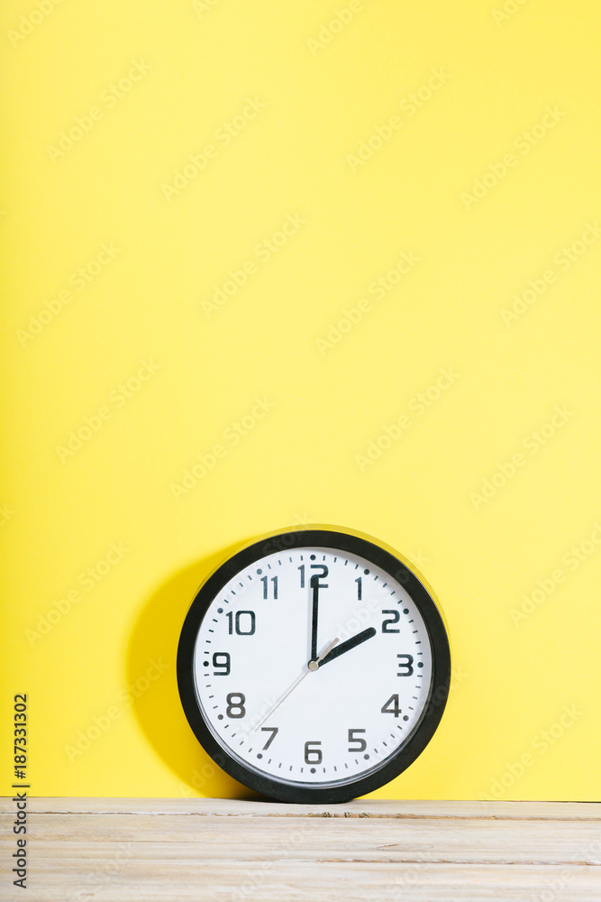 Clock on yellow colored background Stock Photo | Adobe Stock
