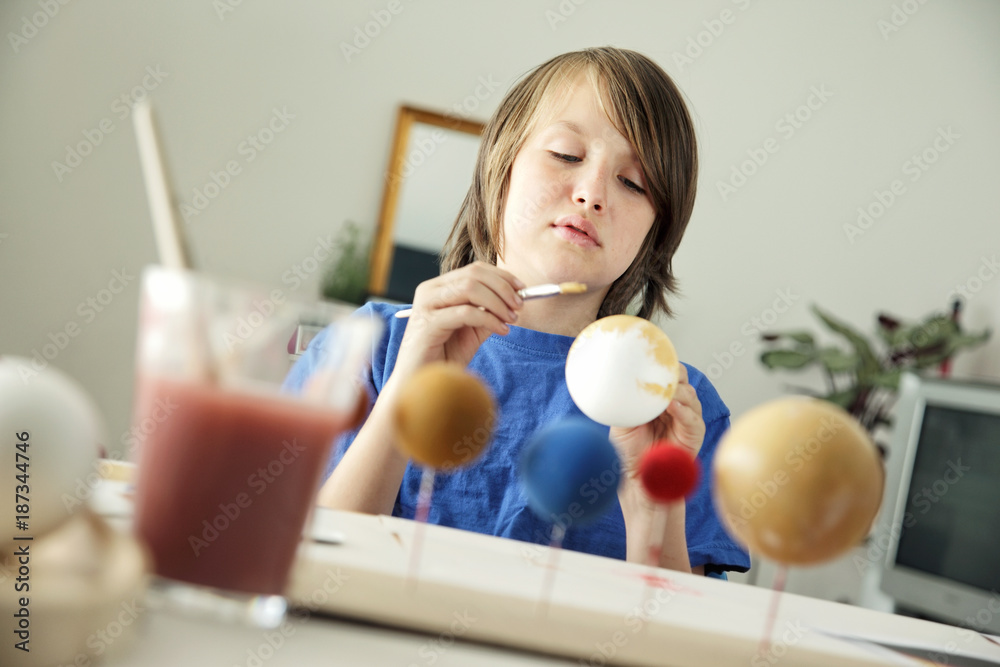 Happy School Boy making a solar system for a school science project at ...