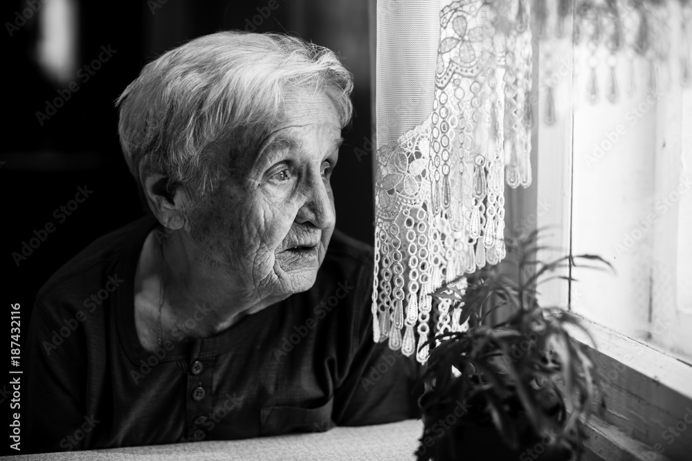 Elderly woman looking sad out the window. Stock-Foto | Adobe Stock
