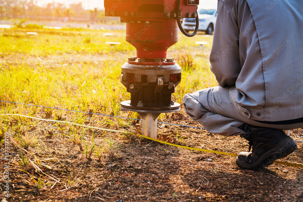 technician installing ground screw for mounting structure of solar ...