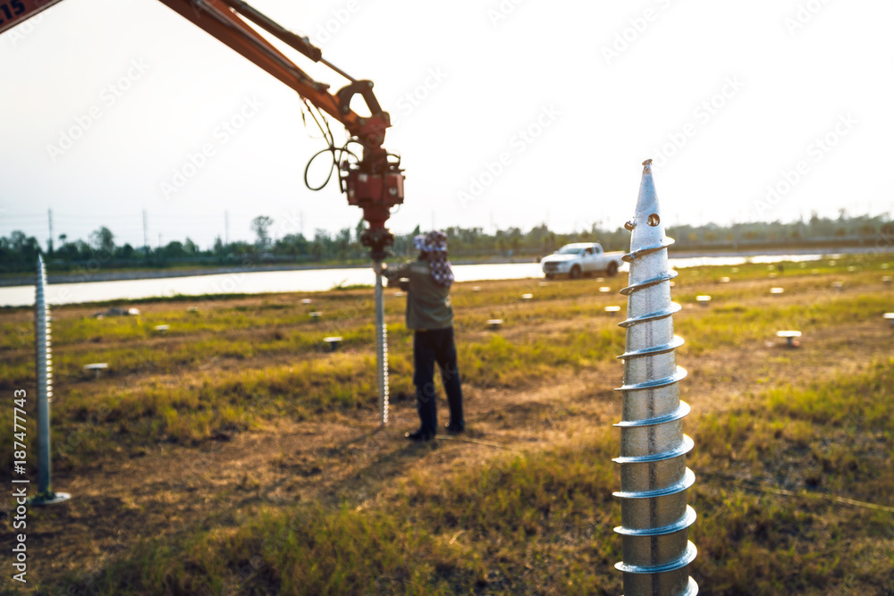 technician installing ground screw for mounting structure of solar ...