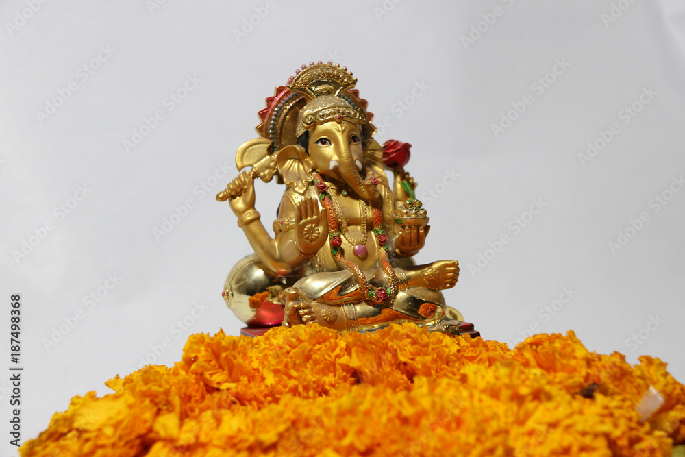 Ganesha made from brass with foreground yellow marigold flower and ...