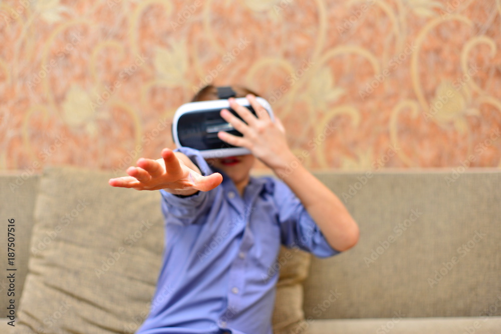 Happy teen boy wearing virtual reality goggles watching movies or ...