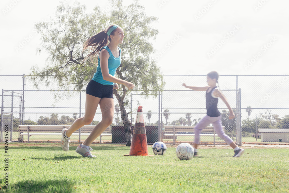 Schoolgirls doing dribbling soccer ball practice on school sports field ...