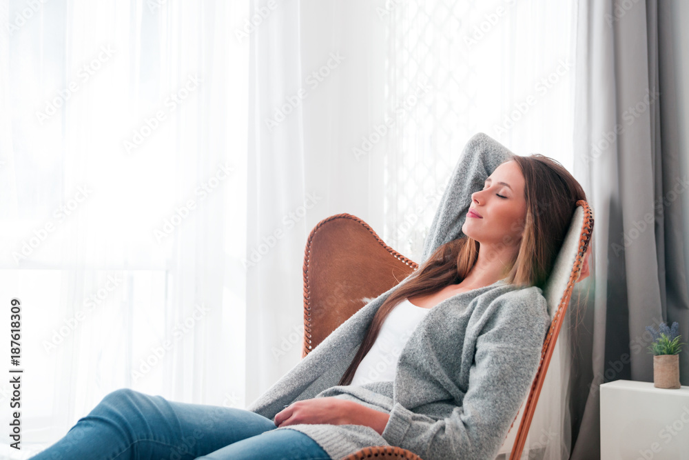 Woman at home sitting on modern chair near window relaxing in living ...
