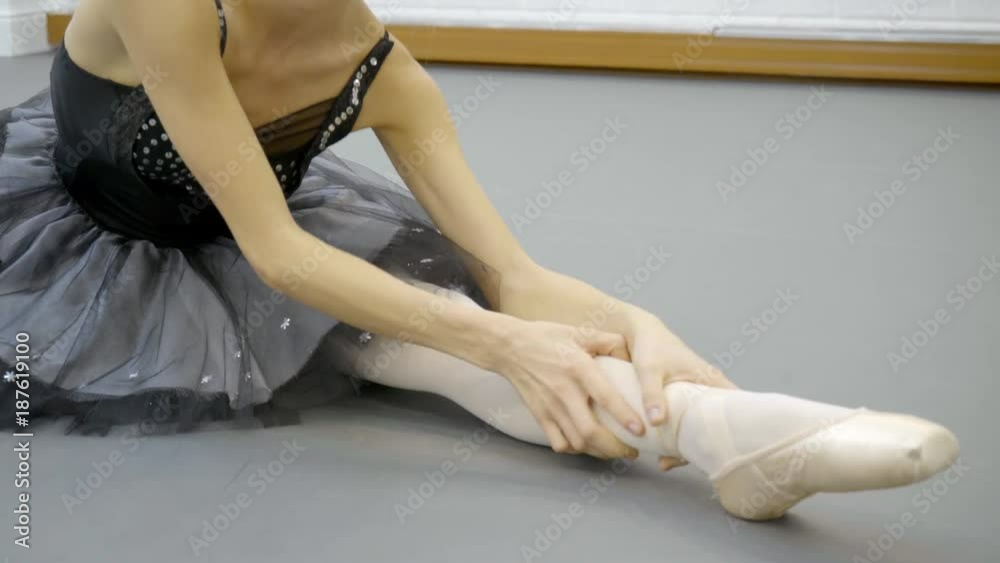 The young ballerina is doing split and inclining to her led to sthetch ...