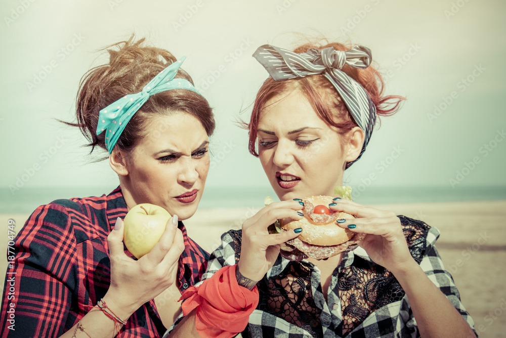 Foto de healthy diet vs junk food concept. two girls eating different ...