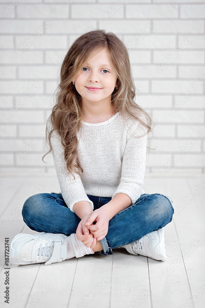 portrait of cute little 7 years old girl smiling and sitting on white ...