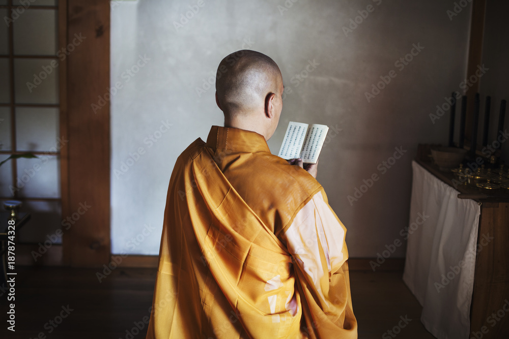 Rear view of Buddhist monk with shaved head wearing golden robe sitting ...