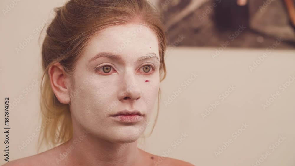 Face art. Makeup artist starting to draw red lines on the model's face ...