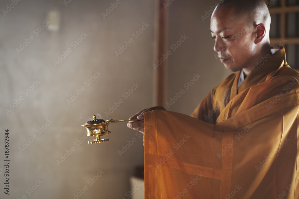 Side view of Buddhist monk with shaved head wearing golden robe ...