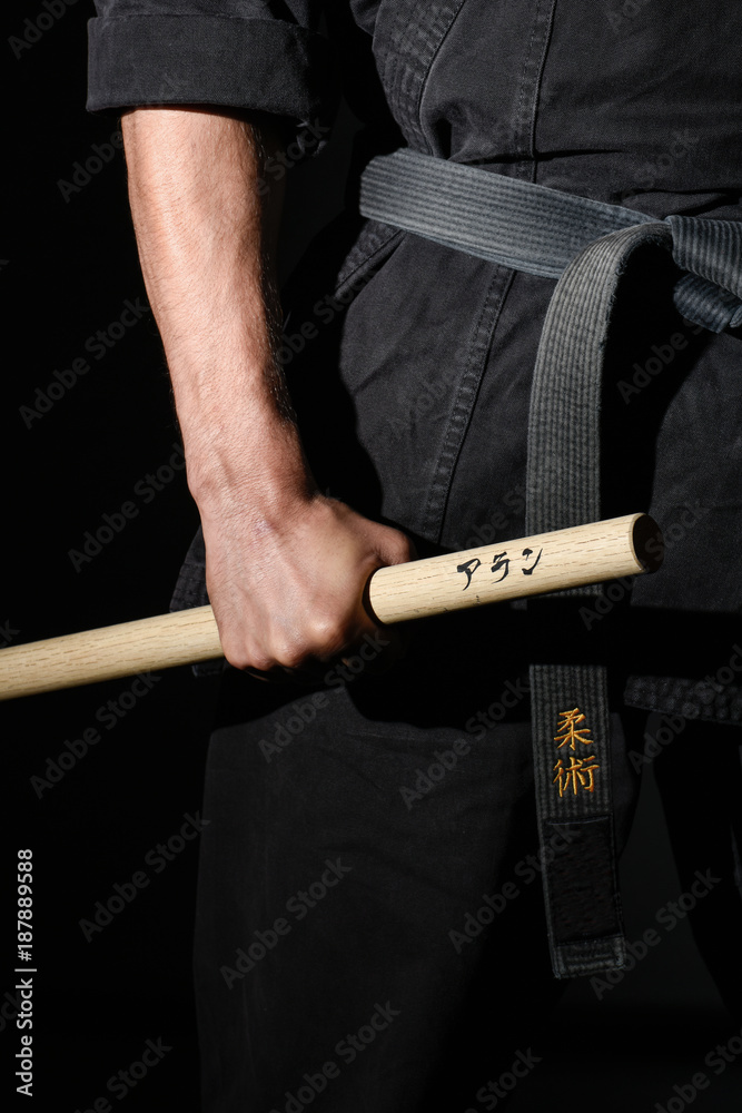 Black judo, aikido, or karate belt, tied in a knot with a hand holding ...