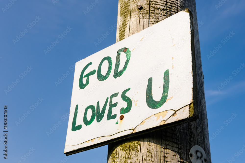 Sign on a lampost with hand-written message "God Loves U", typical of ...