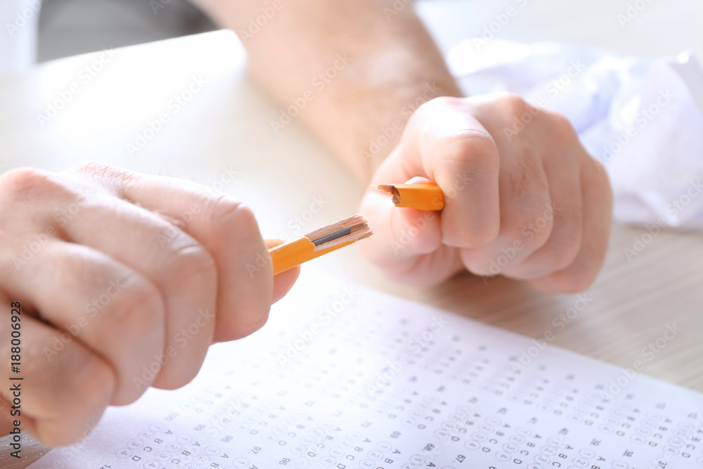 Stressed student breaking pencil while taking exam at table Stock Photo ...