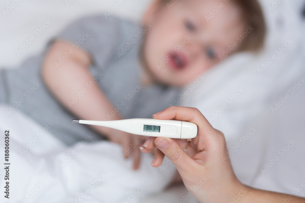 Close-up thermometer with fever heat 38. Mother measuring temperature of her ill kid at ...