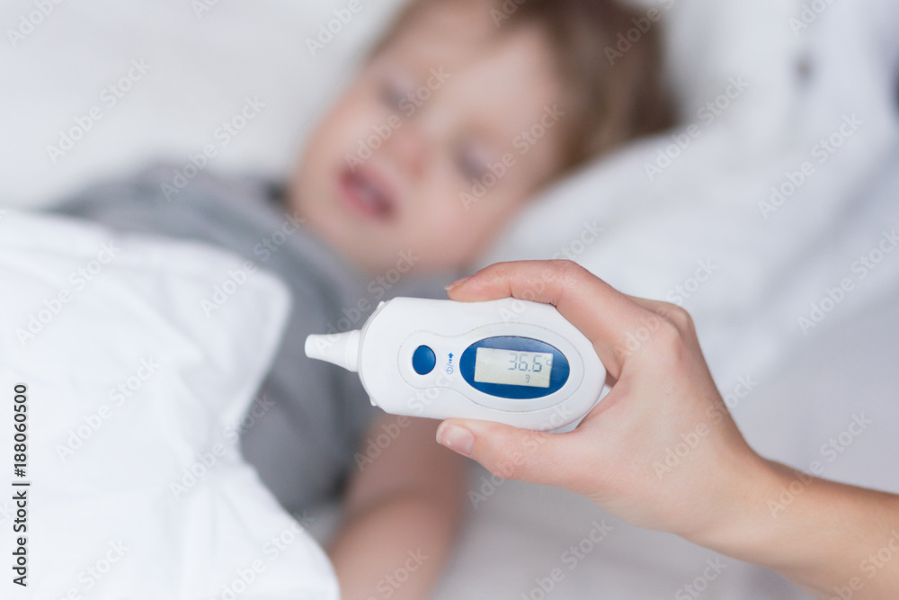Close-up thermometer with fever heat 38. Mother measuring temperature of her ill kid at ...