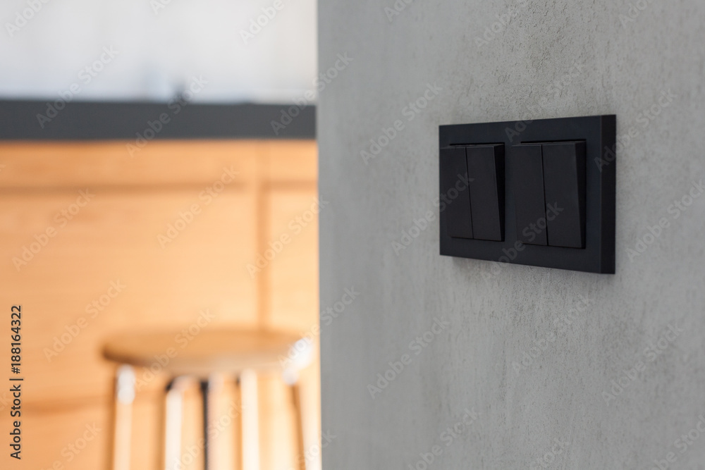 New black switch and socket on the grey wall in the kitchen background ...