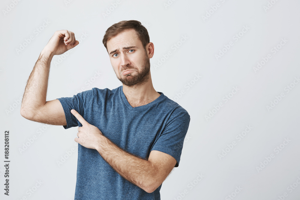 Muscular bearded guy wearing blue t-shirt posing at studio raising arm ...