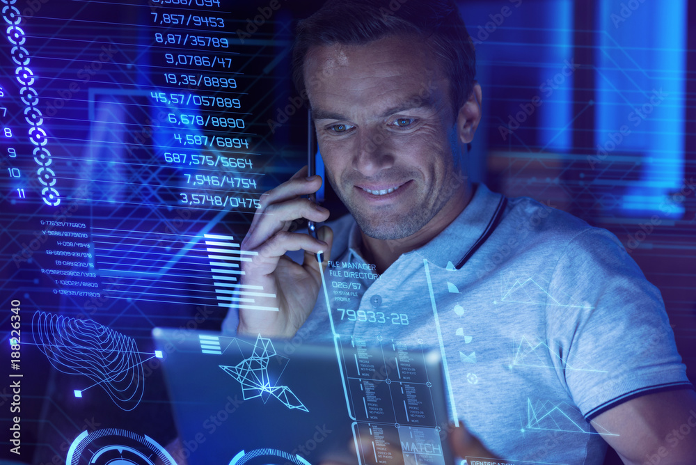 Phone talk. Cheerful handsome young programmer standing in front of a ...