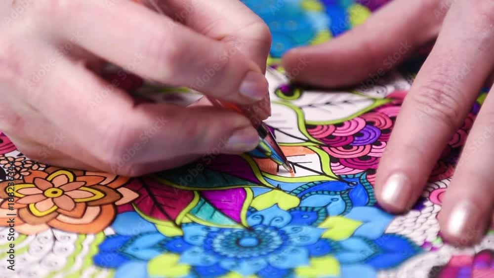 Color video of a young unrecognisable woman colouring in an adult ...