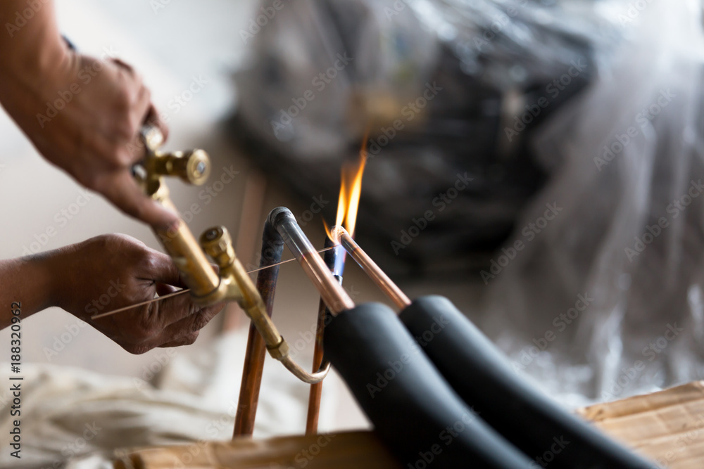 Industry system men worker welds joint of copper pipe air conditioner ...