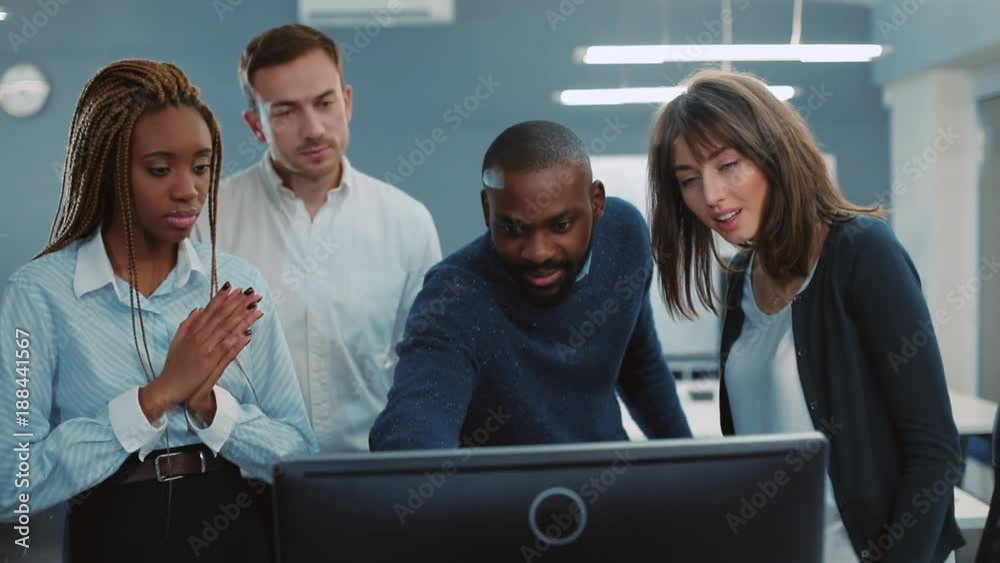 Four office workers watching presentation prepared by one of colleagues ...