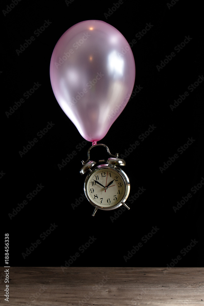 Time flies concept - picture of an old metal clock attached to a pink ...